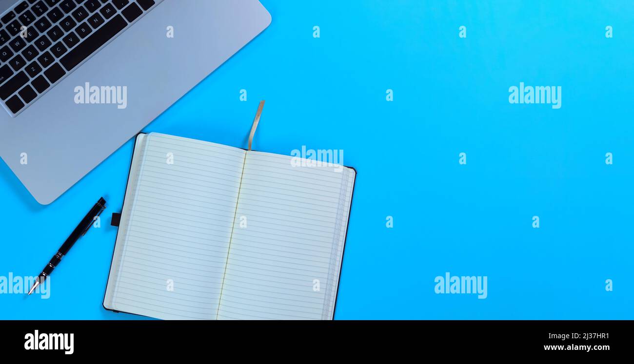 Blue desk table with writing paper, pen, and laptop computer Stock ...
