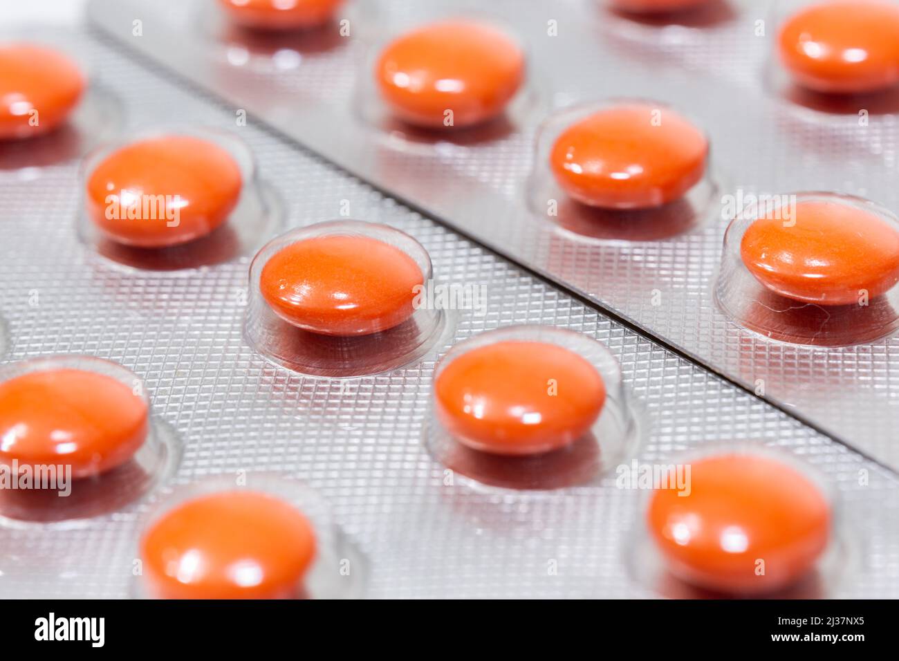 Orange pills in their protective plastic packaging. Selective focus of ...