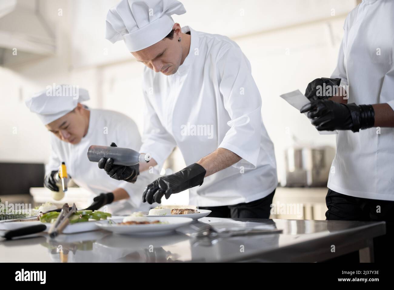 Multiracial group of cooks finishing main courses while working ...