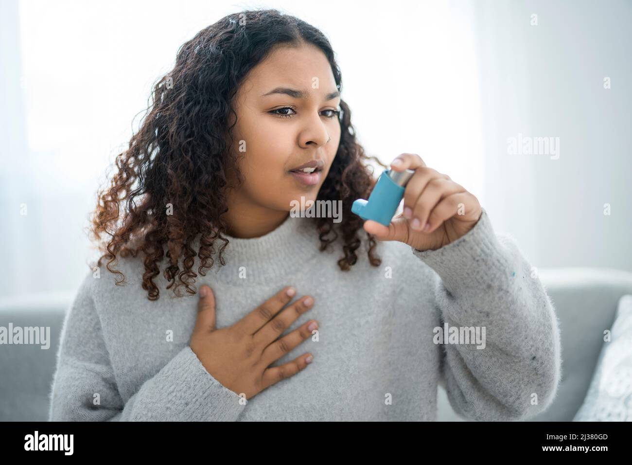 black woman taking her inhaler at home at the living room Stock Photo ...