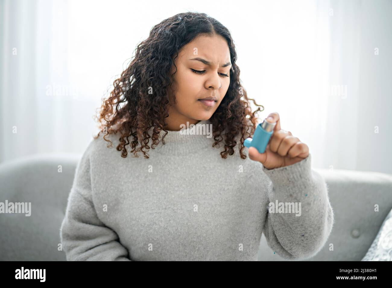 black woman taking her inhaler at home at the living room Stock Photo ...