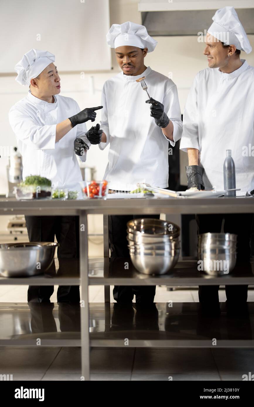 Three cooks with different nationalties tasting cooked meals, inventing ...