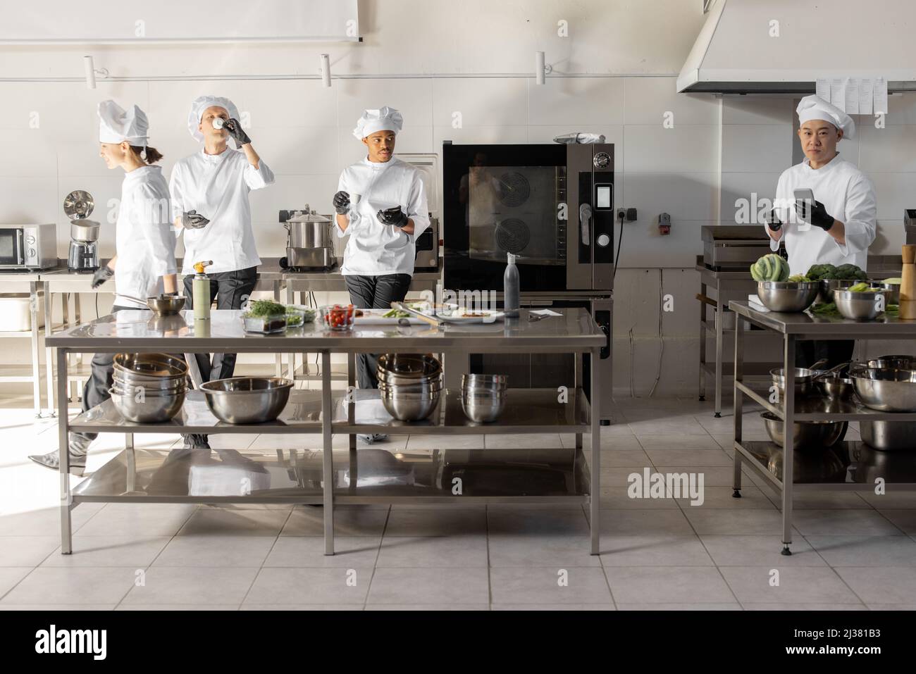 Group of cooks using phones and drinking coffee during a break in the ...