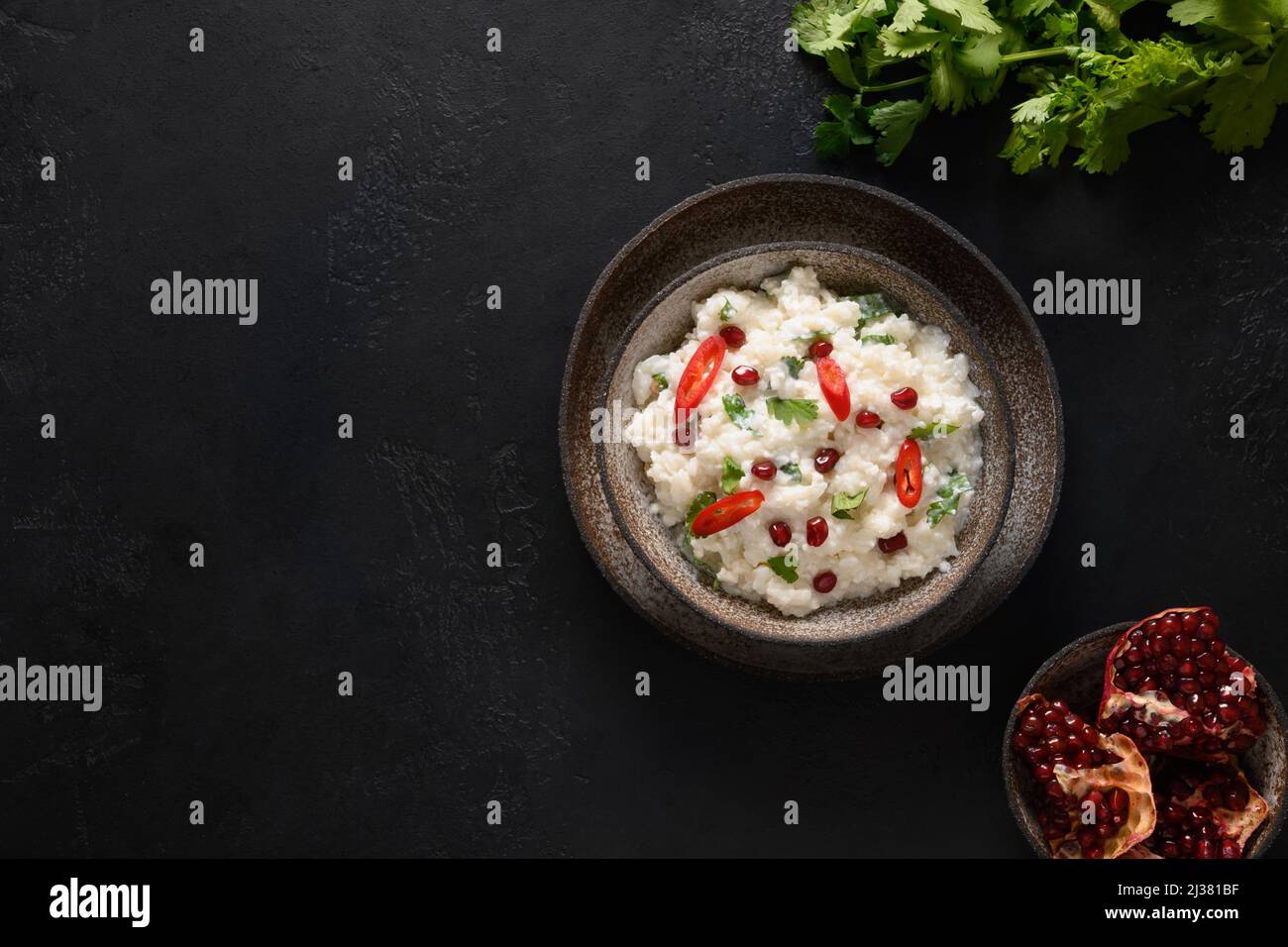 Curd Rice with pomegranate, cilantro, mustard seeds, ginger on a black ...