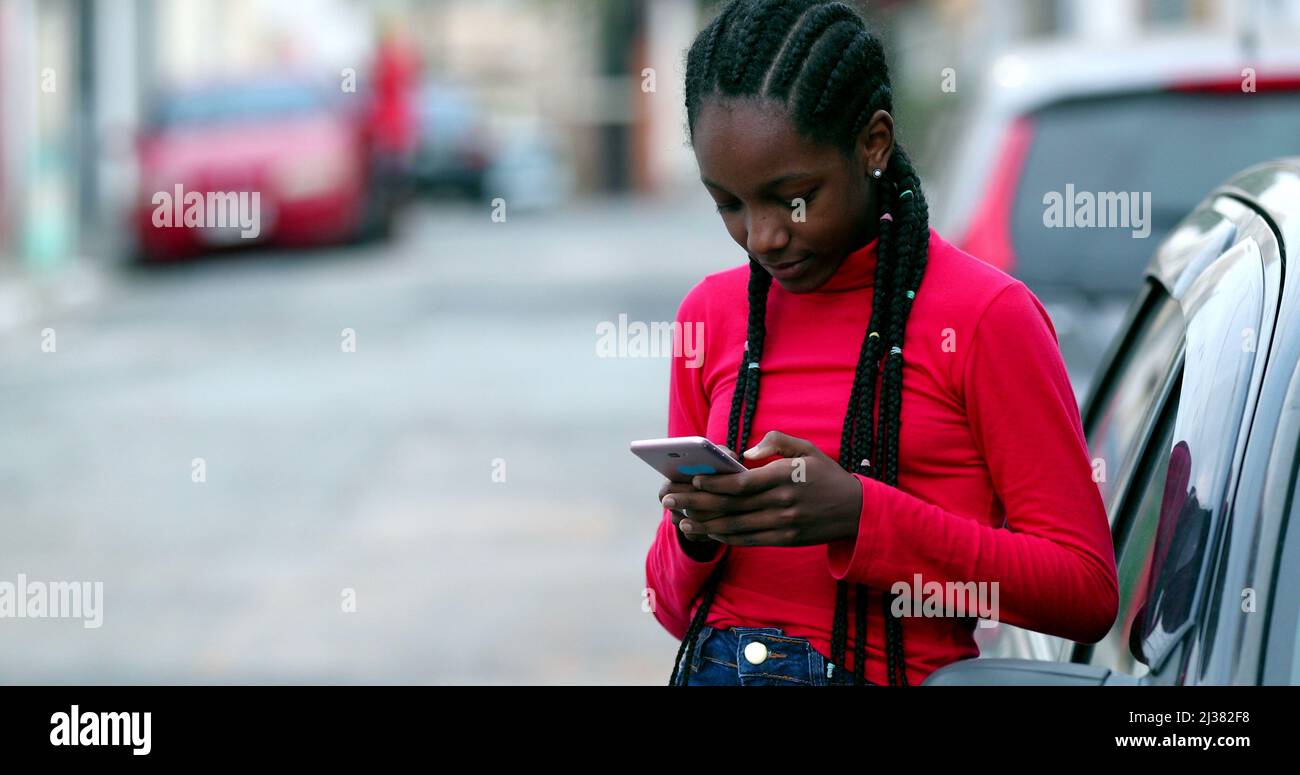Black African girl texting on cellphone outside, Teenager on social ...