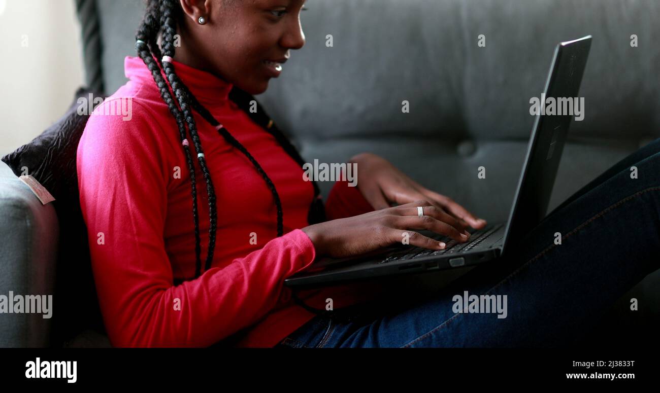 Happy black African teen girl using laptop computer at home Stock Photo ...