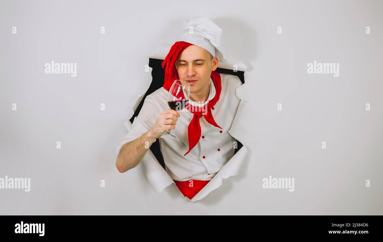 Male cook drinking alcoholic beverage and sticking out of hole of white ...