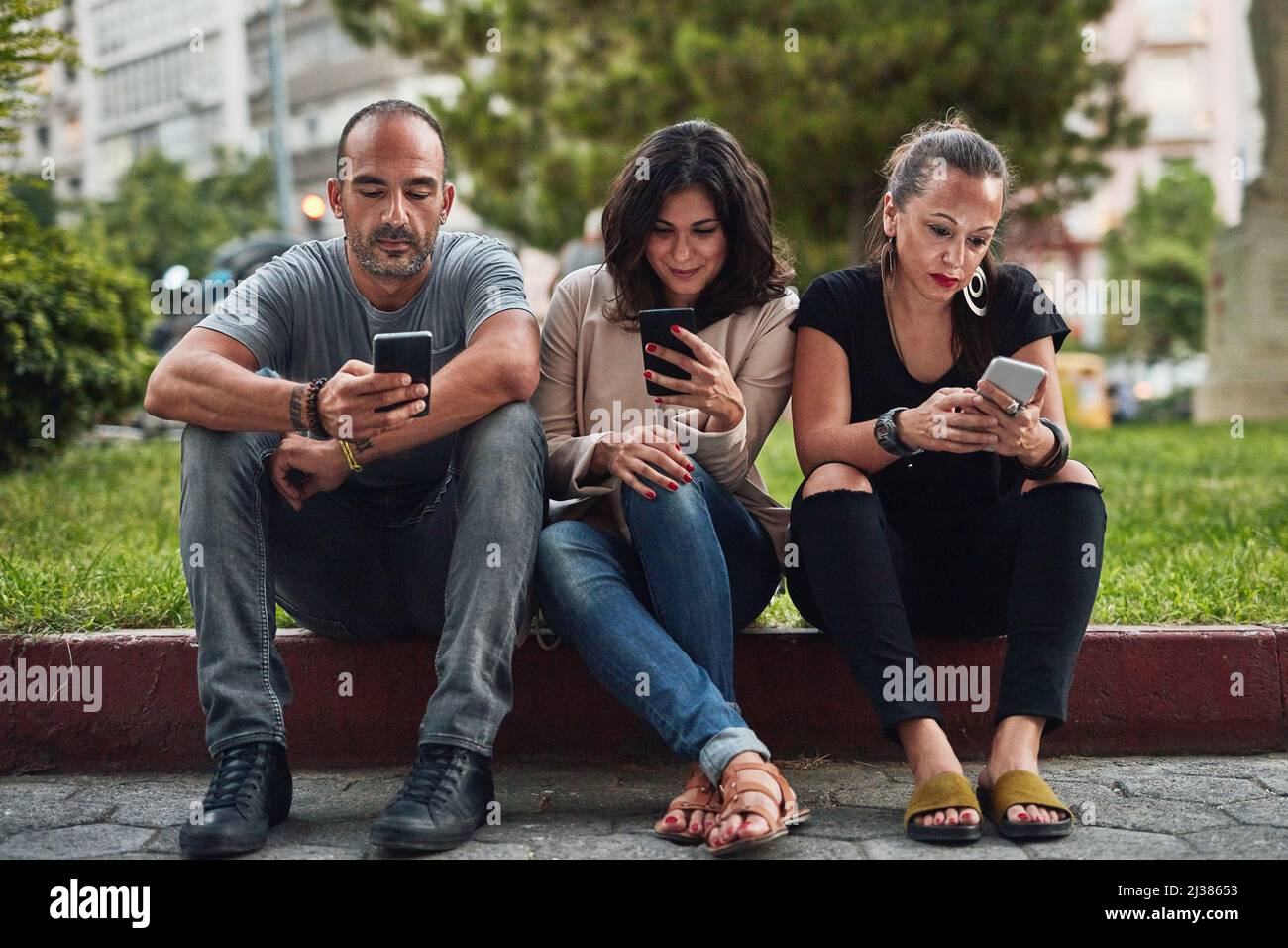 Growing apart as technology grows. Shot of three friends using their ...