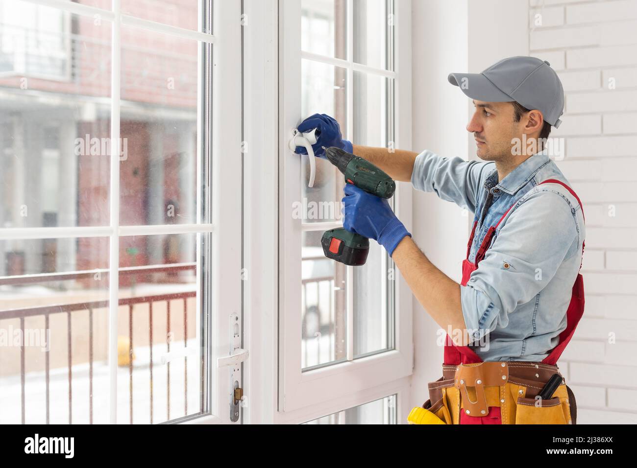 handsome young man installing bay window in a new house construction ...