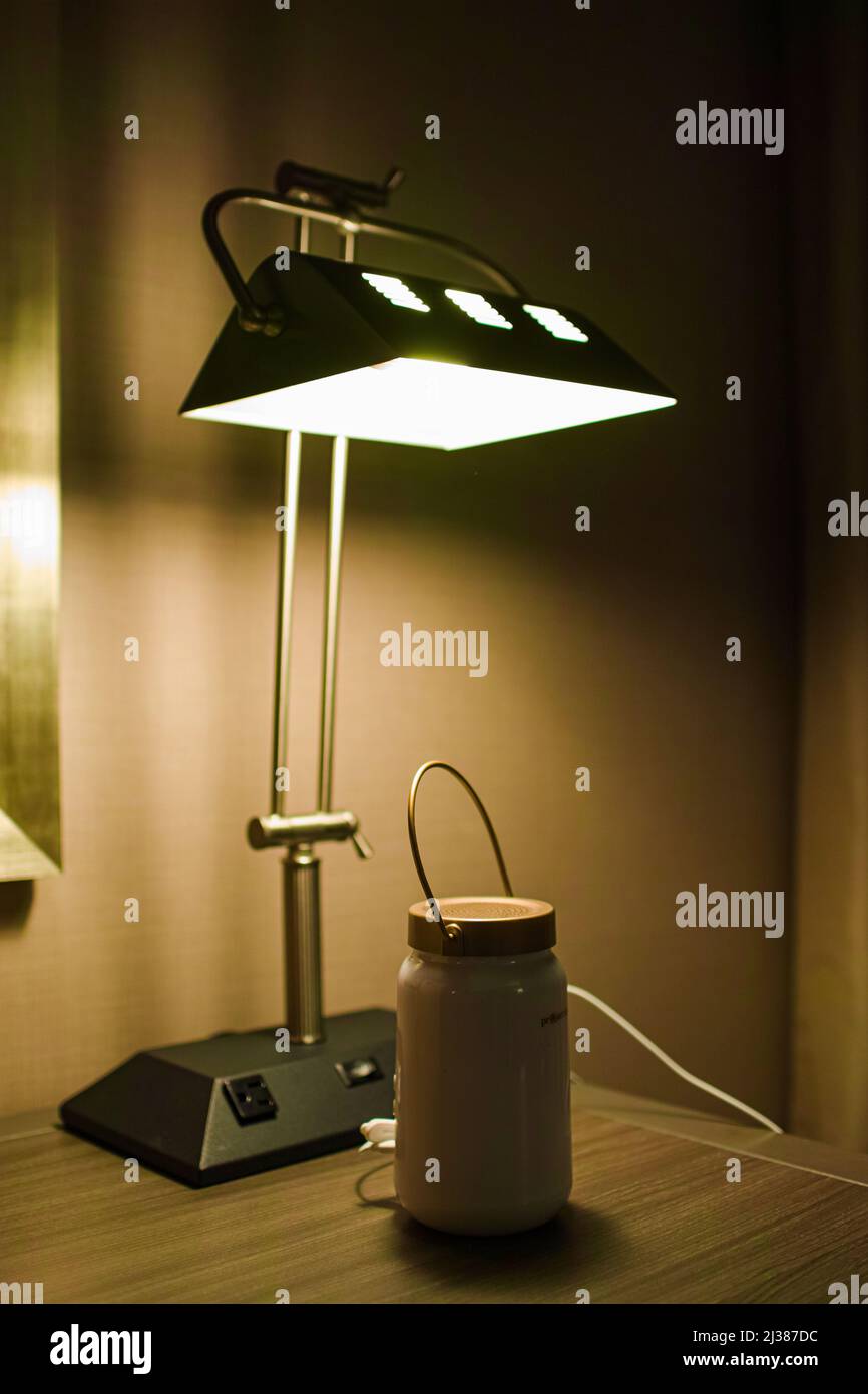 A vertical shot of a beautiful modern lamp shining on a wooden table ...
