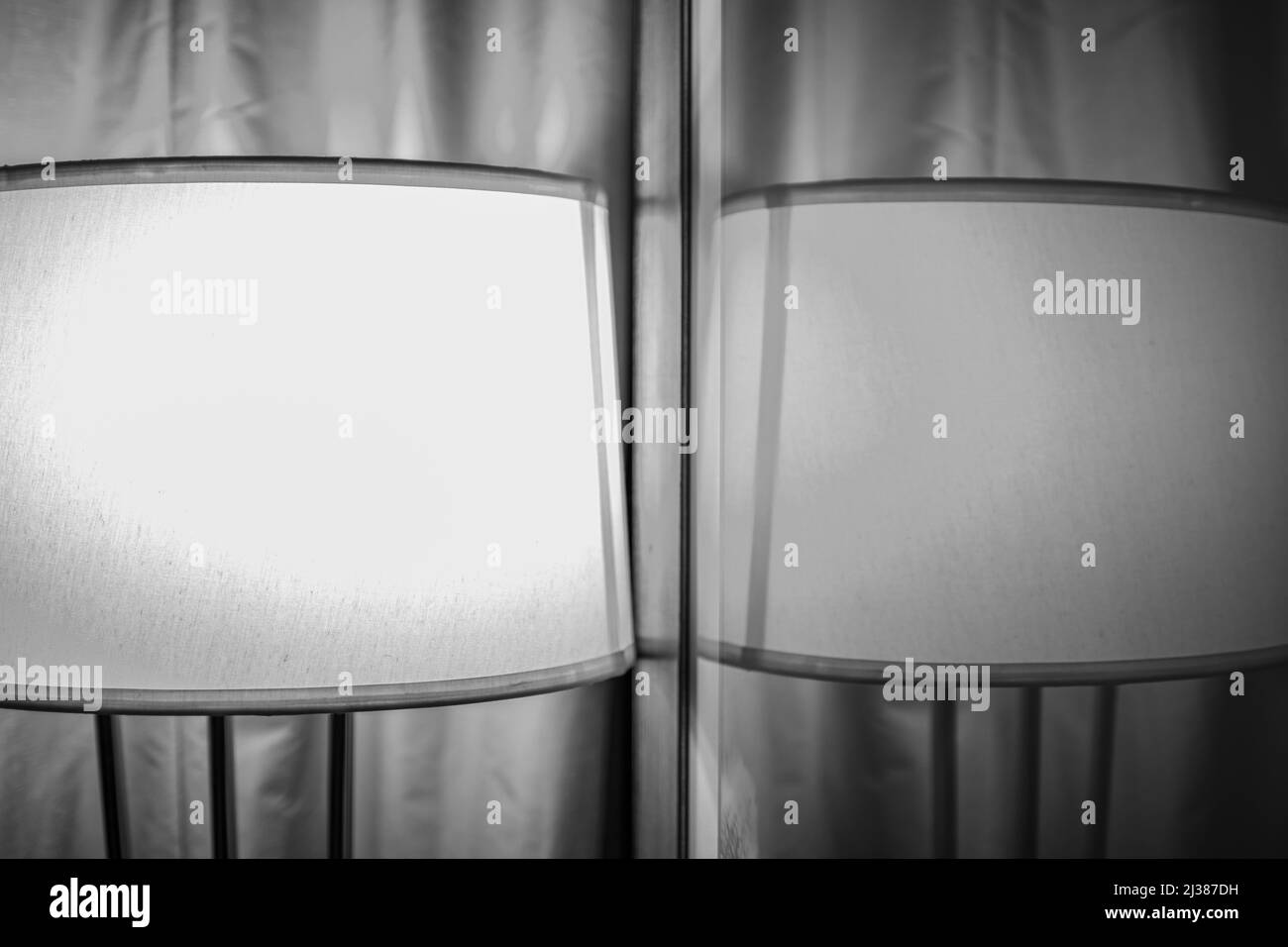 A grayscale shot of a lamp shining with its reflection on the mirror ...