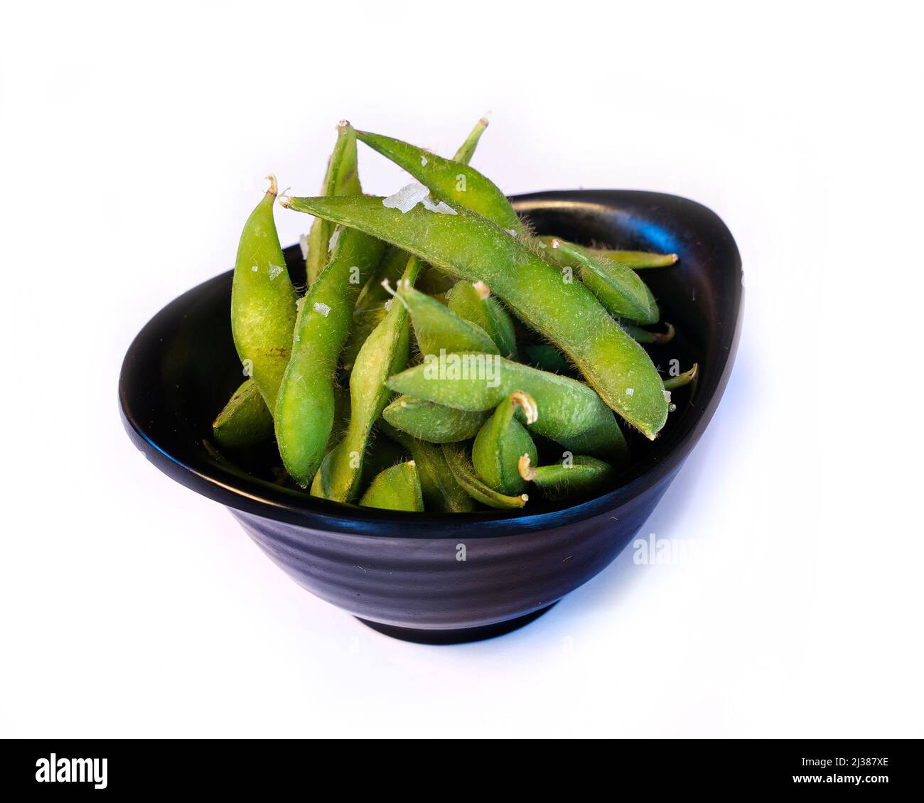 A closeup of traditional Japanese dish edamame in a black bowl isolated ...
