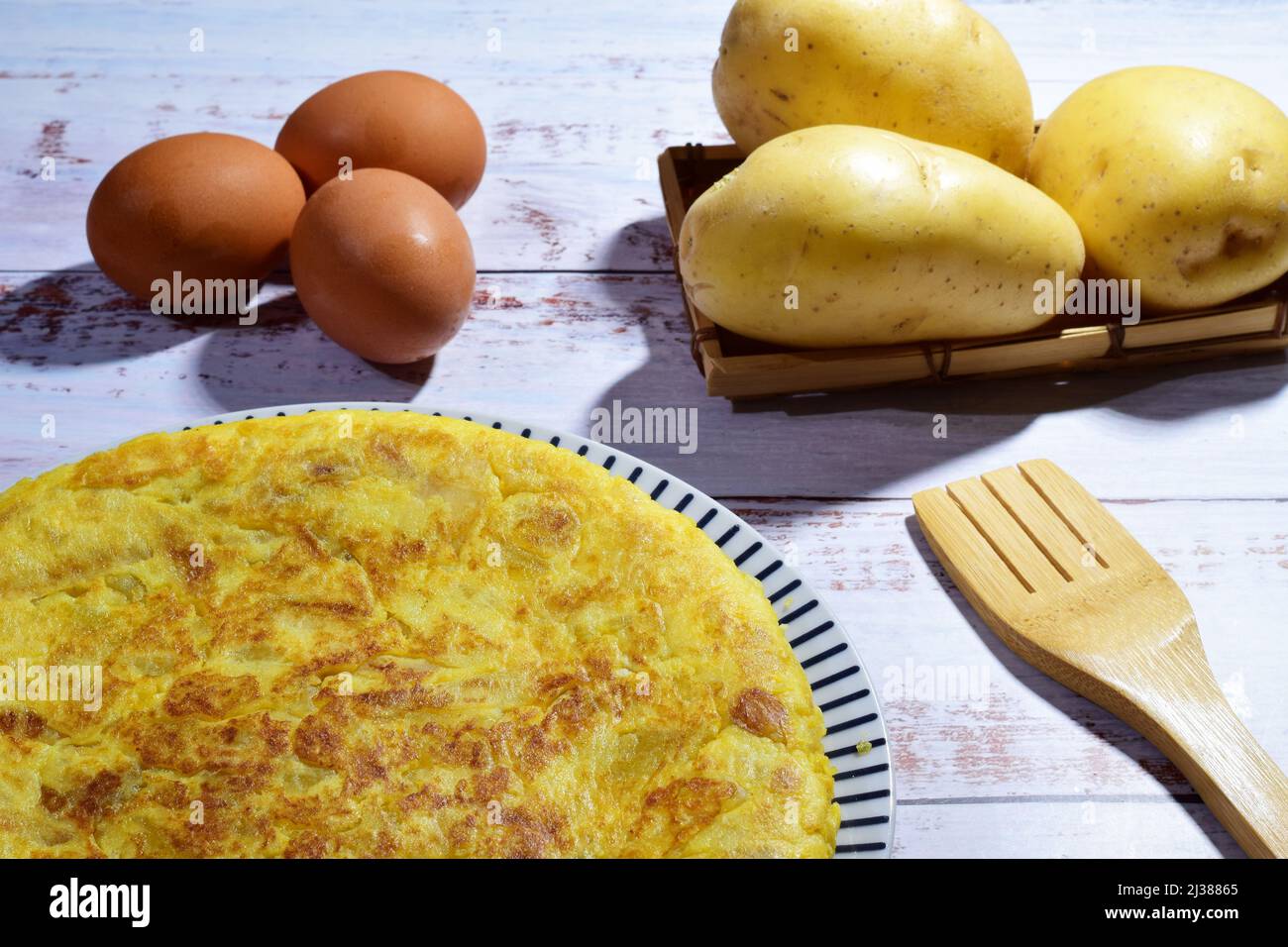 An omelet in a plate, potatoes, eggs and a wooden fork on a table Stock ...