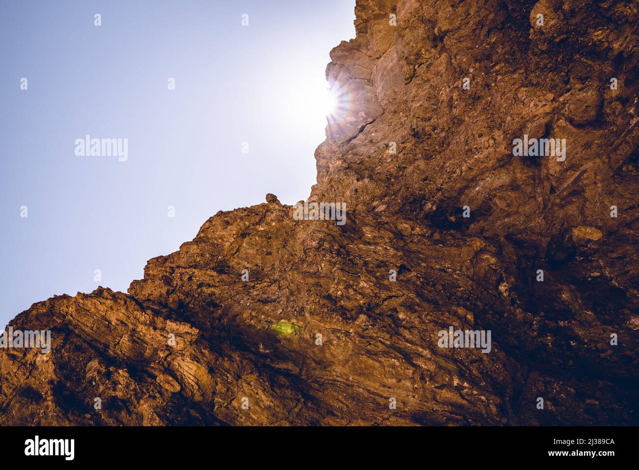 A low angel shot of a rock in a mountain with sunrays perpendicular ...