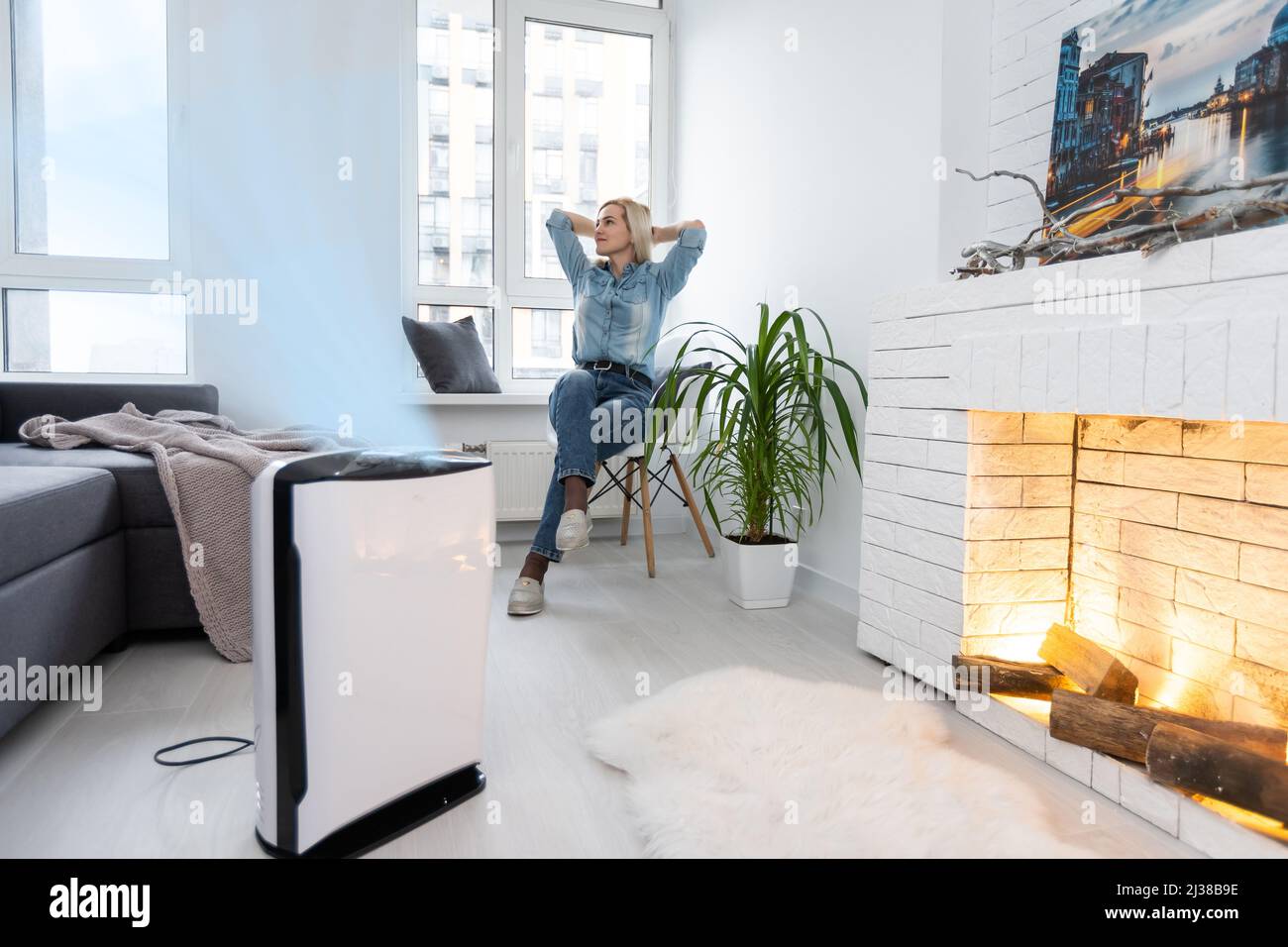 Woman relaxing at home with working air humidifier on the foreground ...
