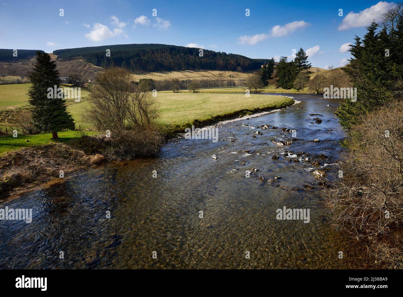 A sunny view upstream of the River Esk from the bridge at Bentpath ...