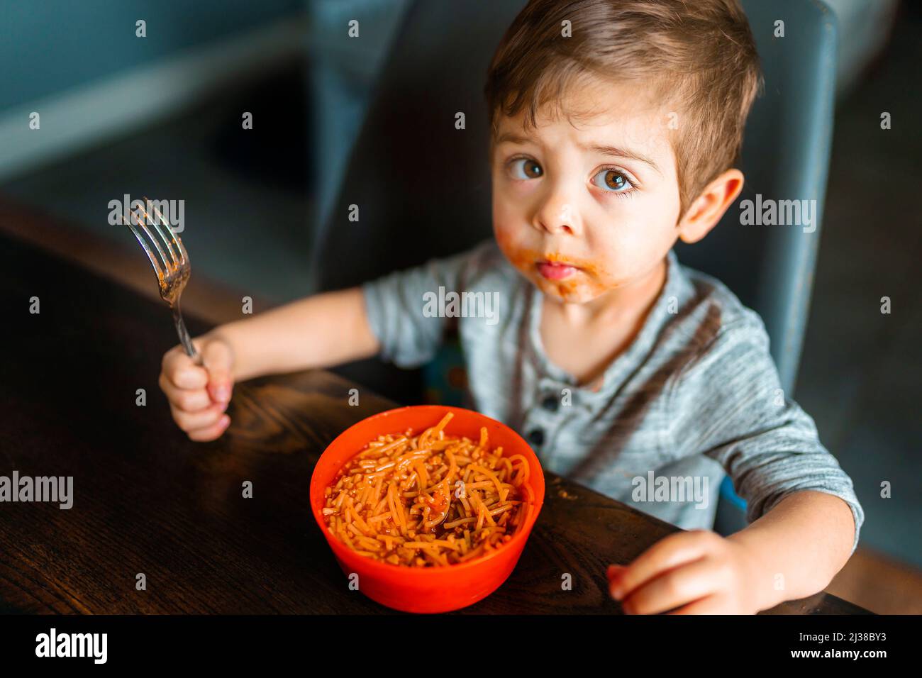 Kid eating spaghetti in the kitchen having fun Stock Photo - Alamy