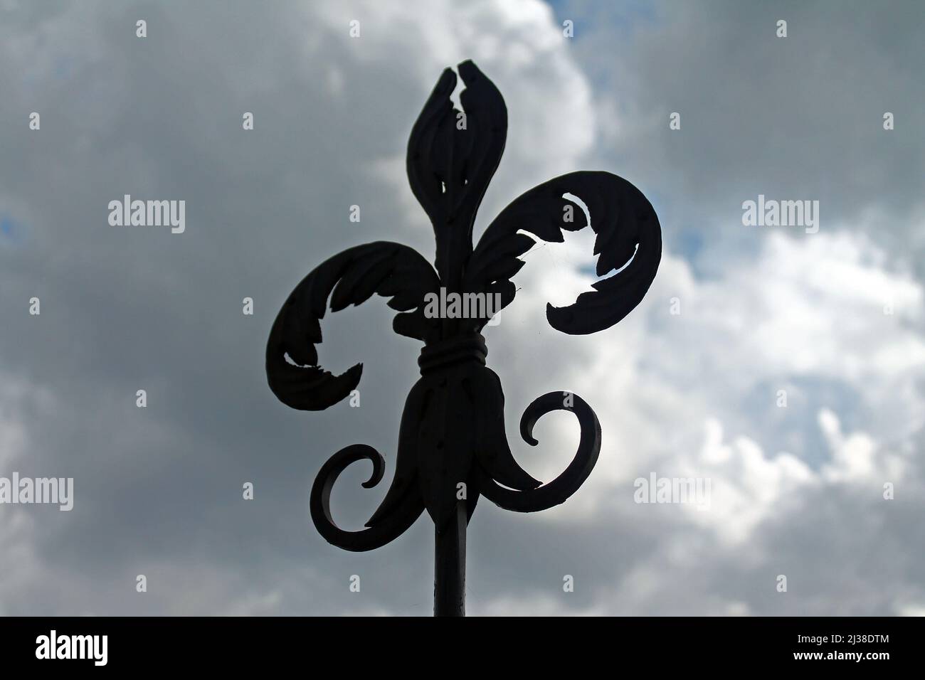 The iron lily on the top of a tower with a dramatic clouded sky in ...