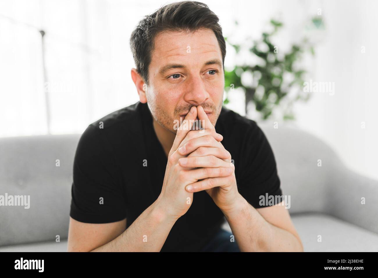 Depressed man thinking at home on couch Stock Photo - Alamy