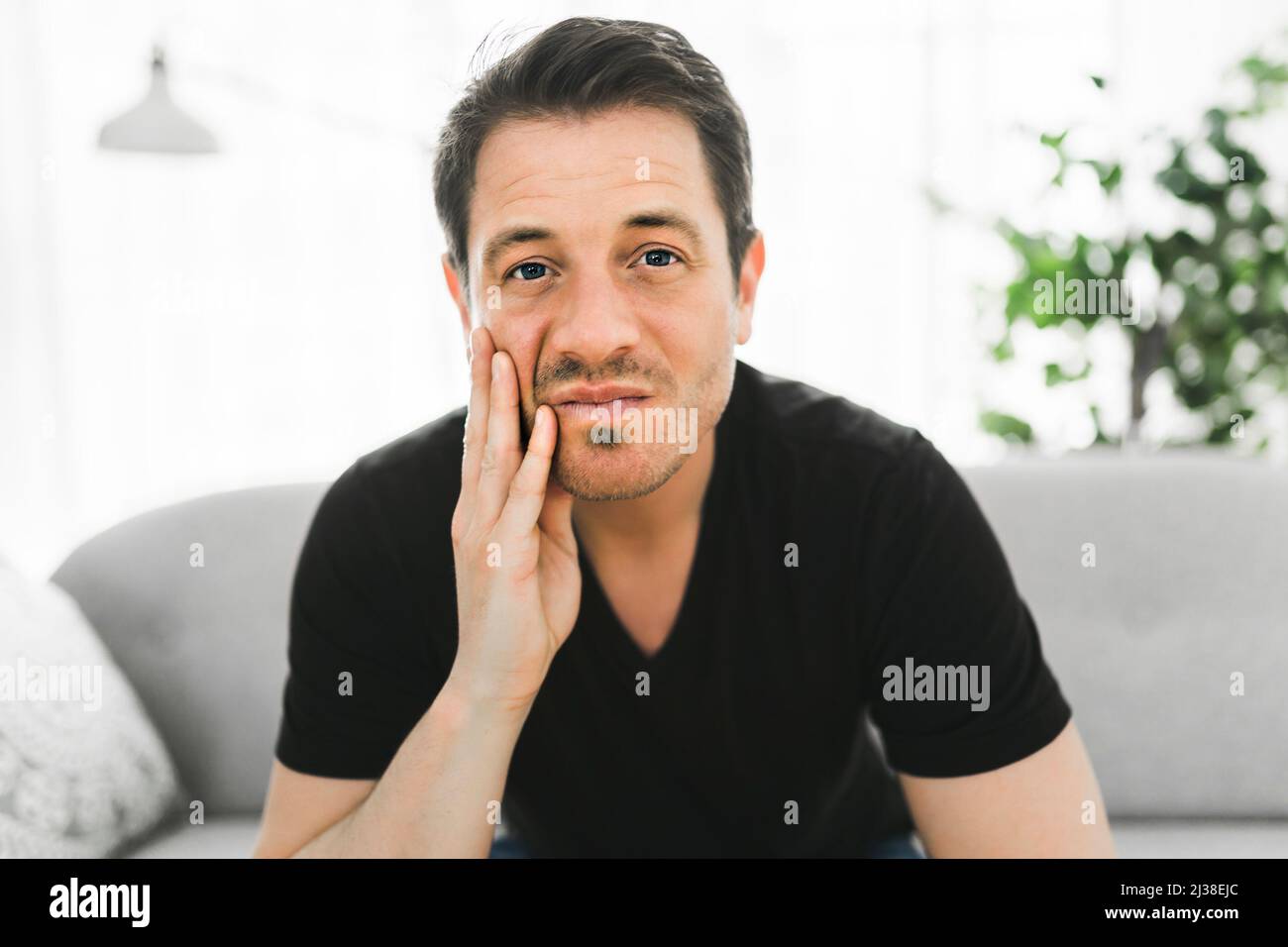 Depressed man thinking at home on couch Stock Photo - Alamy