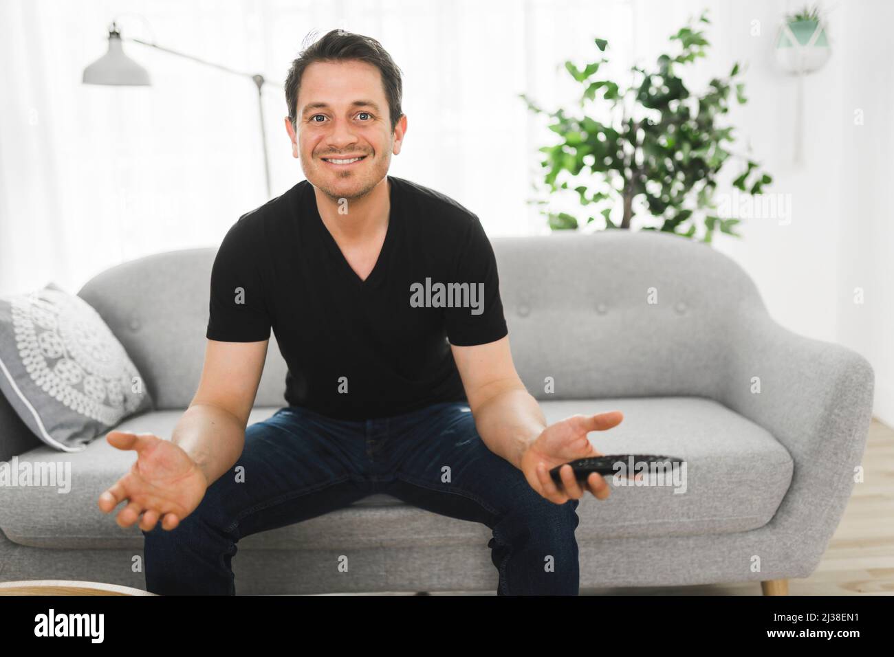 portrait of fashionable trendy looking young European man watching TV ...