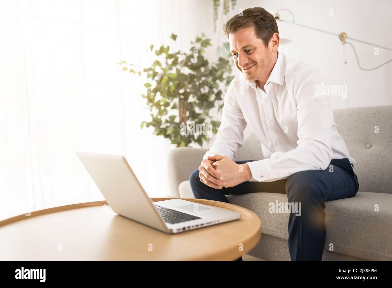 Happy smiling young man watching and working on computer laptop at home ...