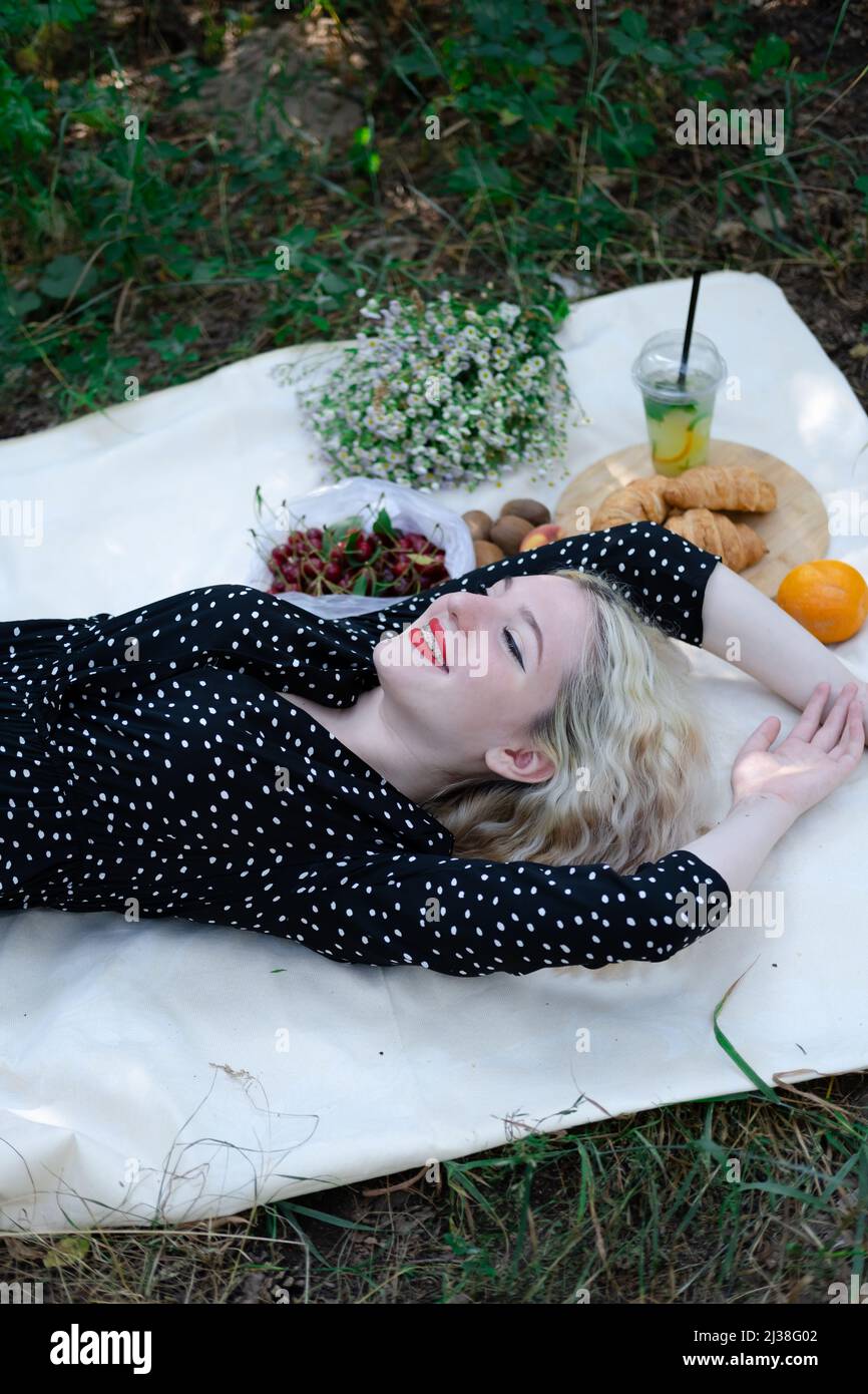 pretty blonde girl on a picnic in a forest or park with lemonade ...