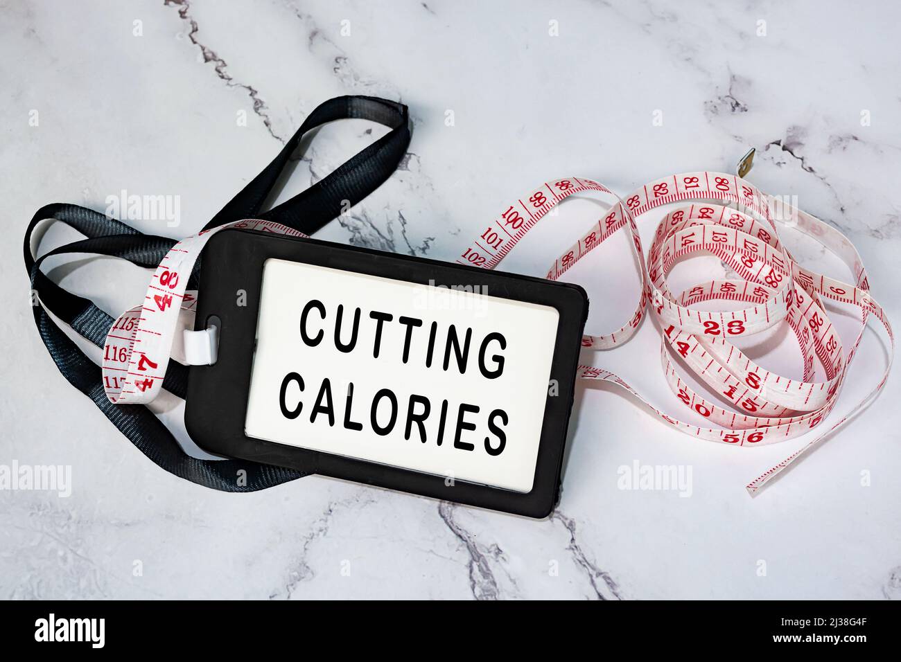 Cutting calories on black name tag with measure tap on white desk ...
