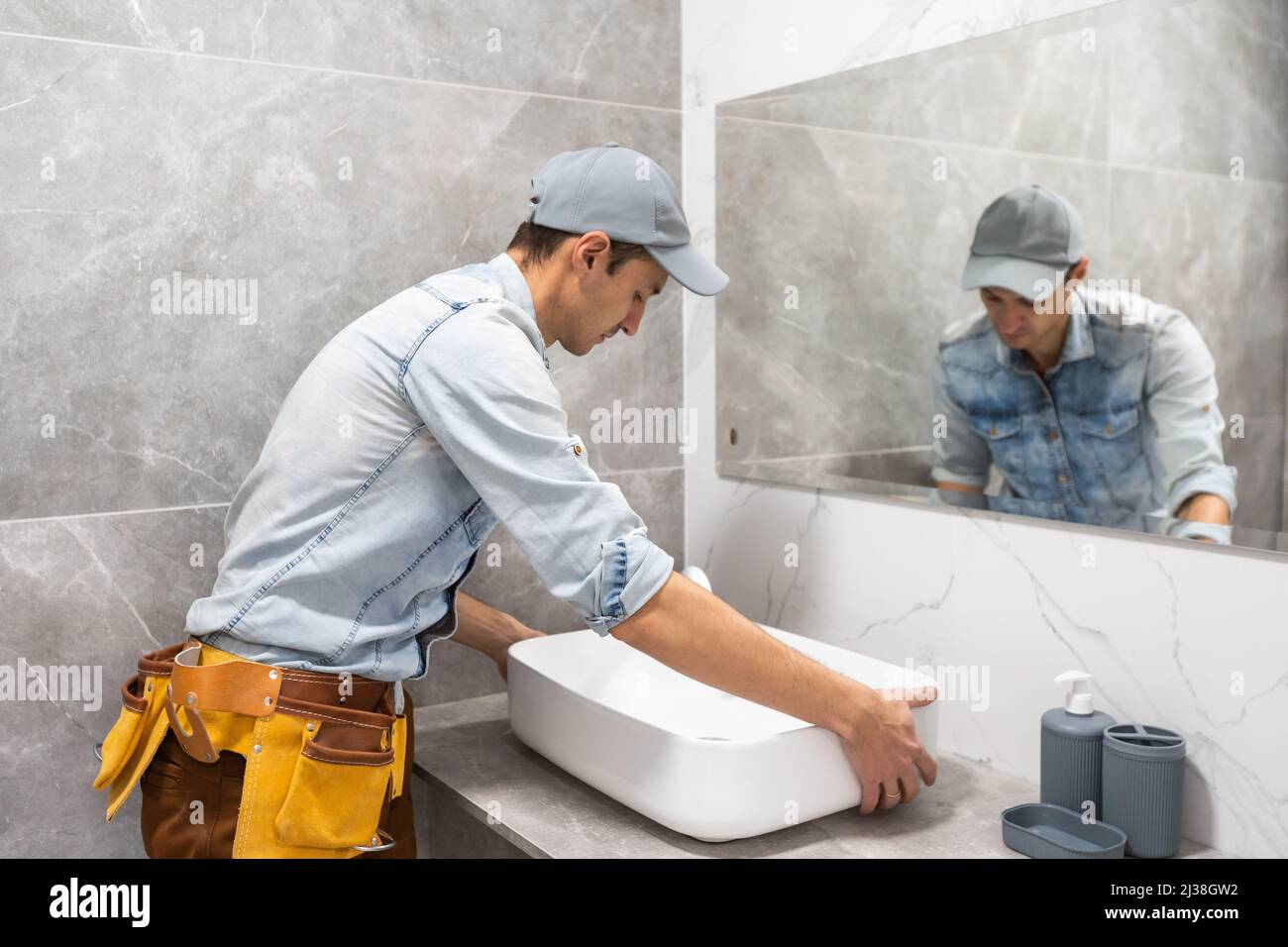 Professional plumber, male worker in uniform installing sink and water ...