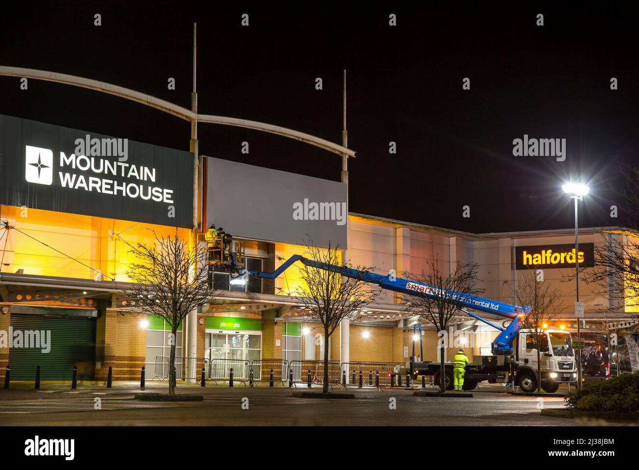 Service workers make repairs to a large retail unit on a retail site at ...