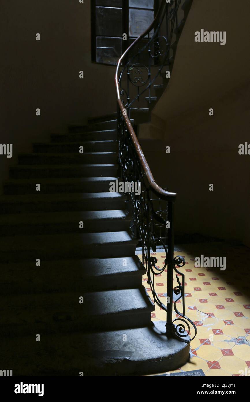 An ancient staircase with a wrought-iron balustrade in the dark ...