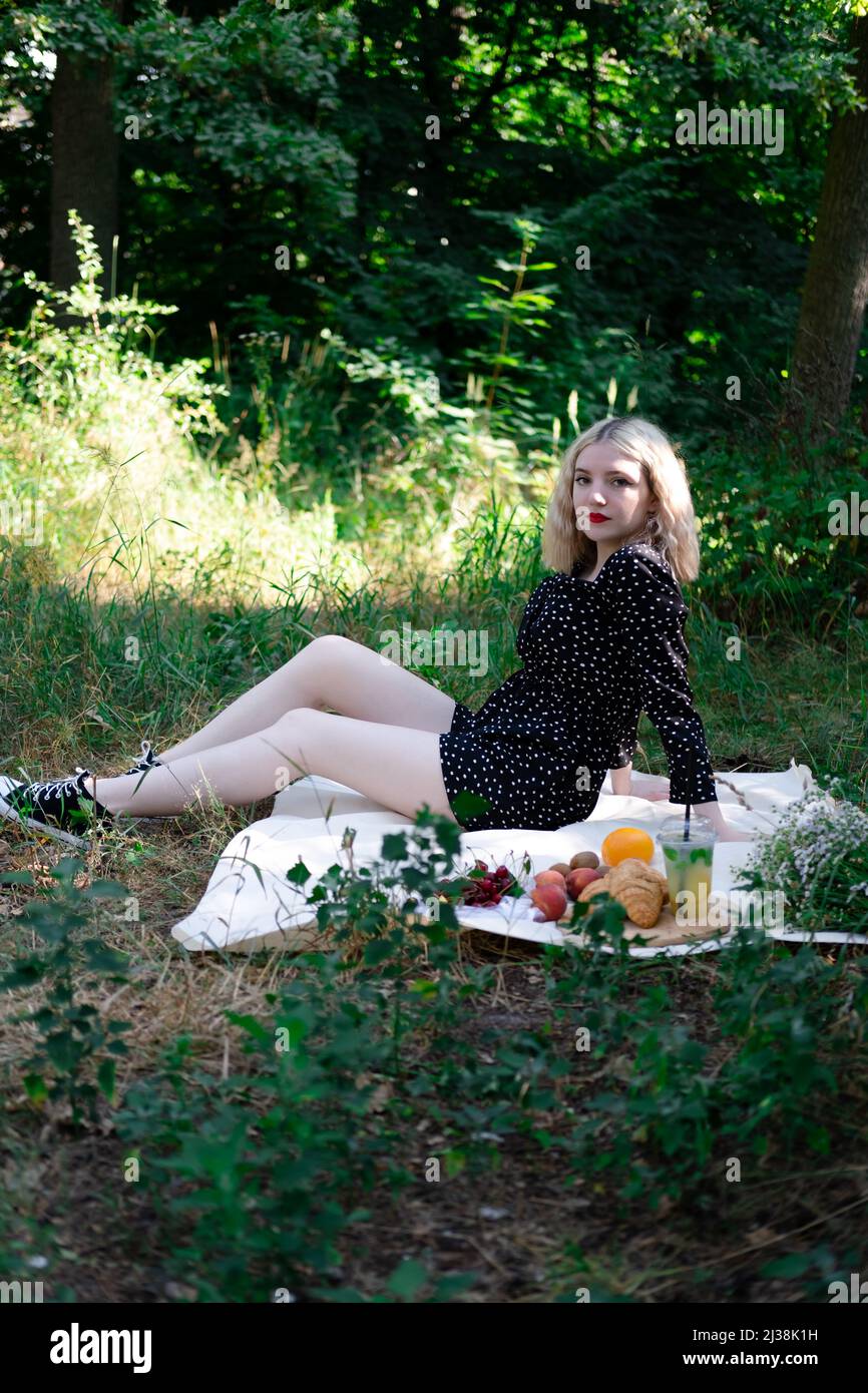 pretty blonde girl on a picnic in a forest or park with lemonade ...