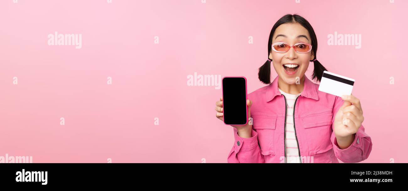 Asian girl shows mobile phone screen and credit card, reacts surprised ...