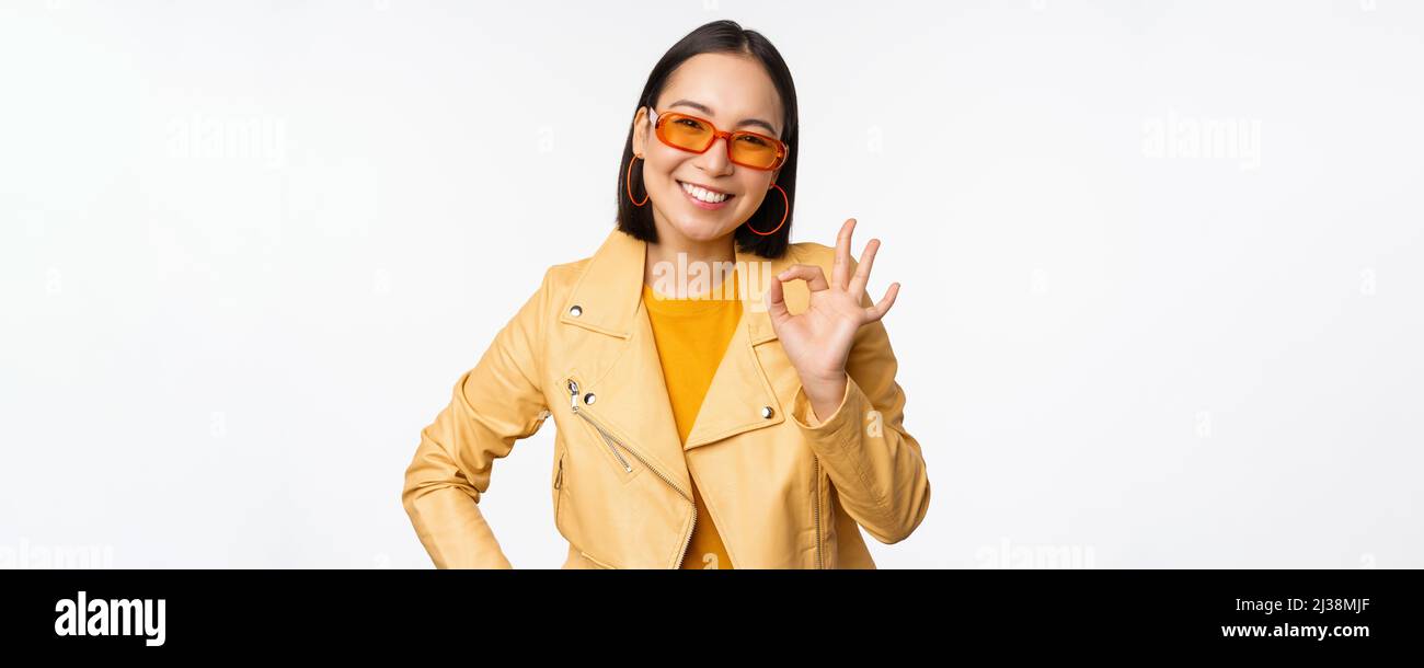 Excellent. Smiling asian girl shows okay, ok sign, nod in approval ...