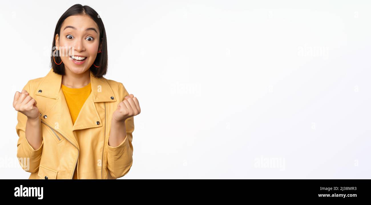 Surprised and happy asian girl, looking with happy face of rejoice ...