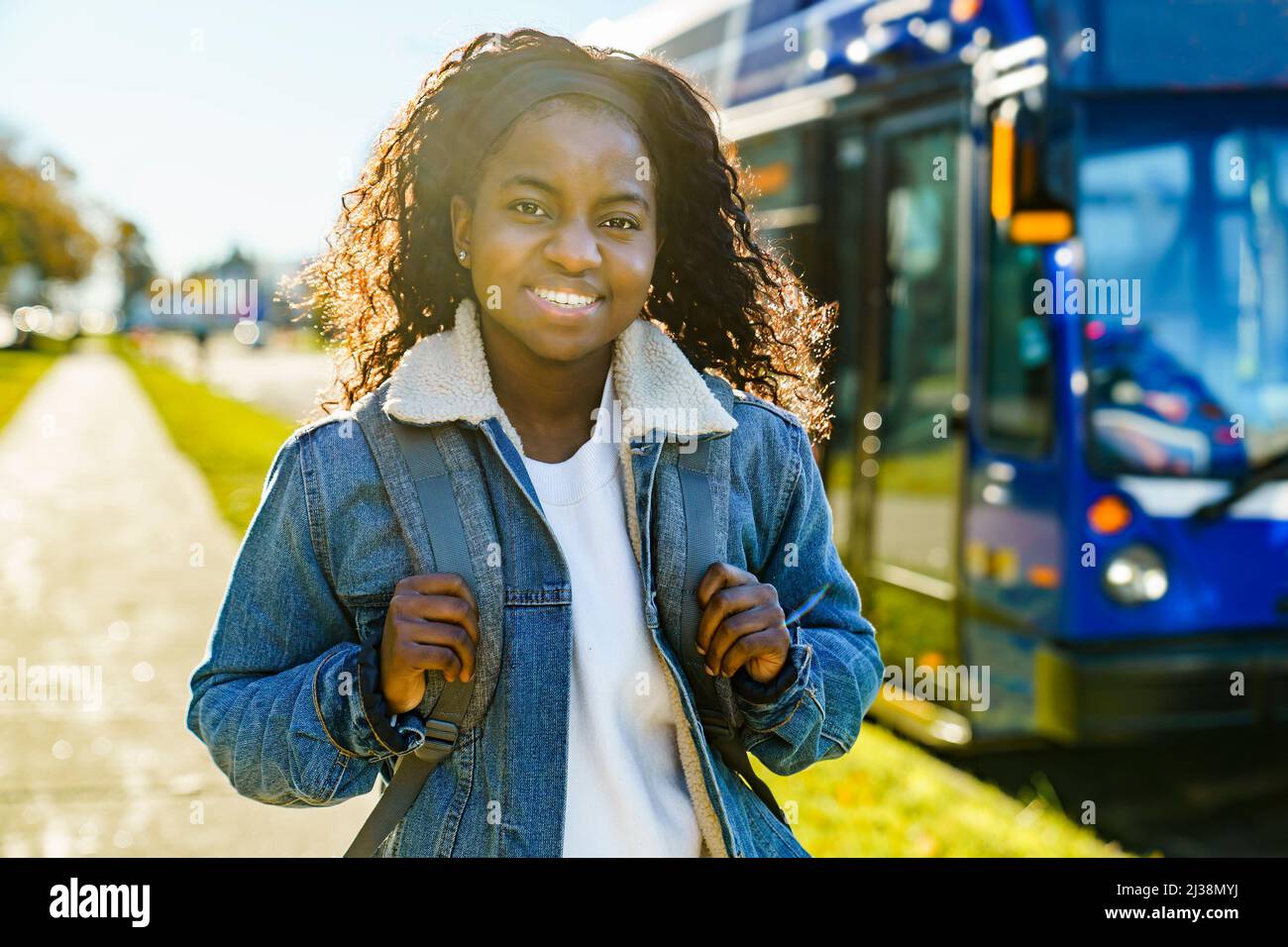 pretty african american woman with backpack close to the bus station ...