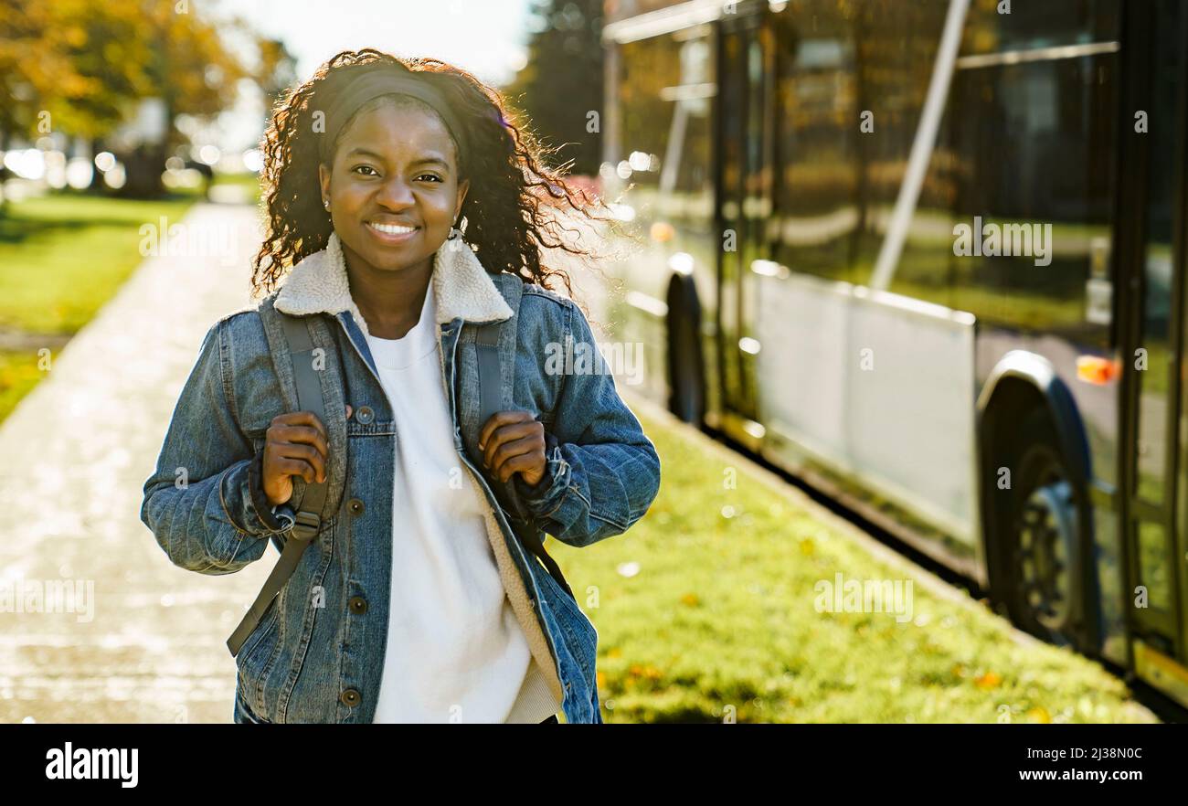 pretty african american woman with backpack close to the bus station ...