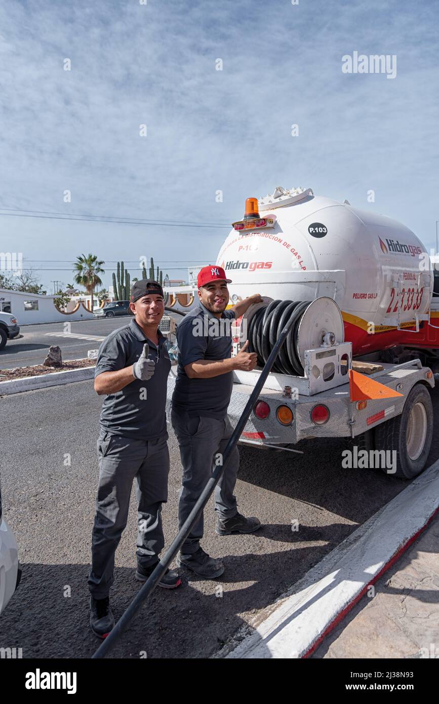 Two workers wearing clean, grey uniforms, stand by a large red and ...