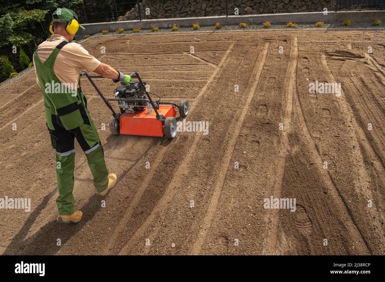 Landscaping Worker Preparing Backyard Garden Soil For a Natural Grass ...