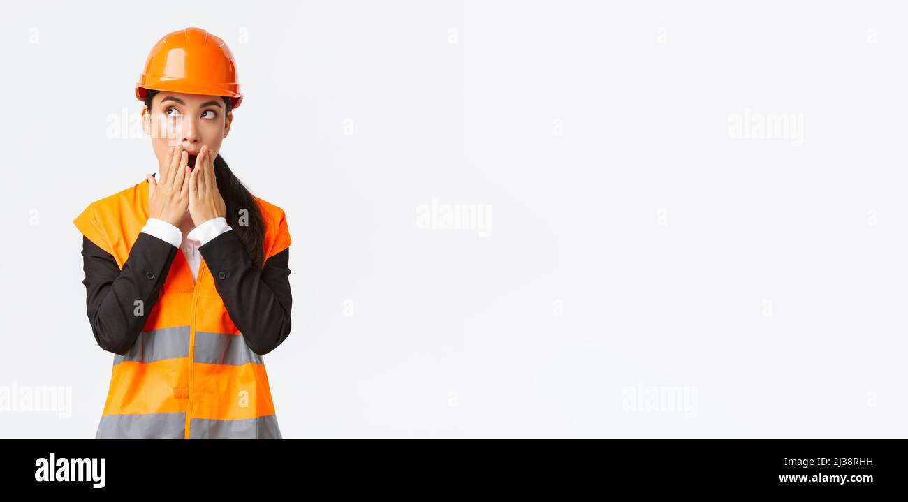 Shocked and concerned asian female engineer, architect in safety helmet ...