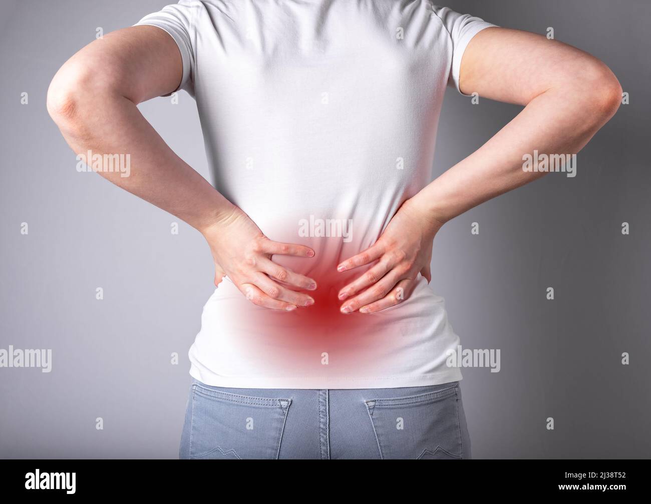 Backache. Woman suffering from lower back pain with red point closeup ...