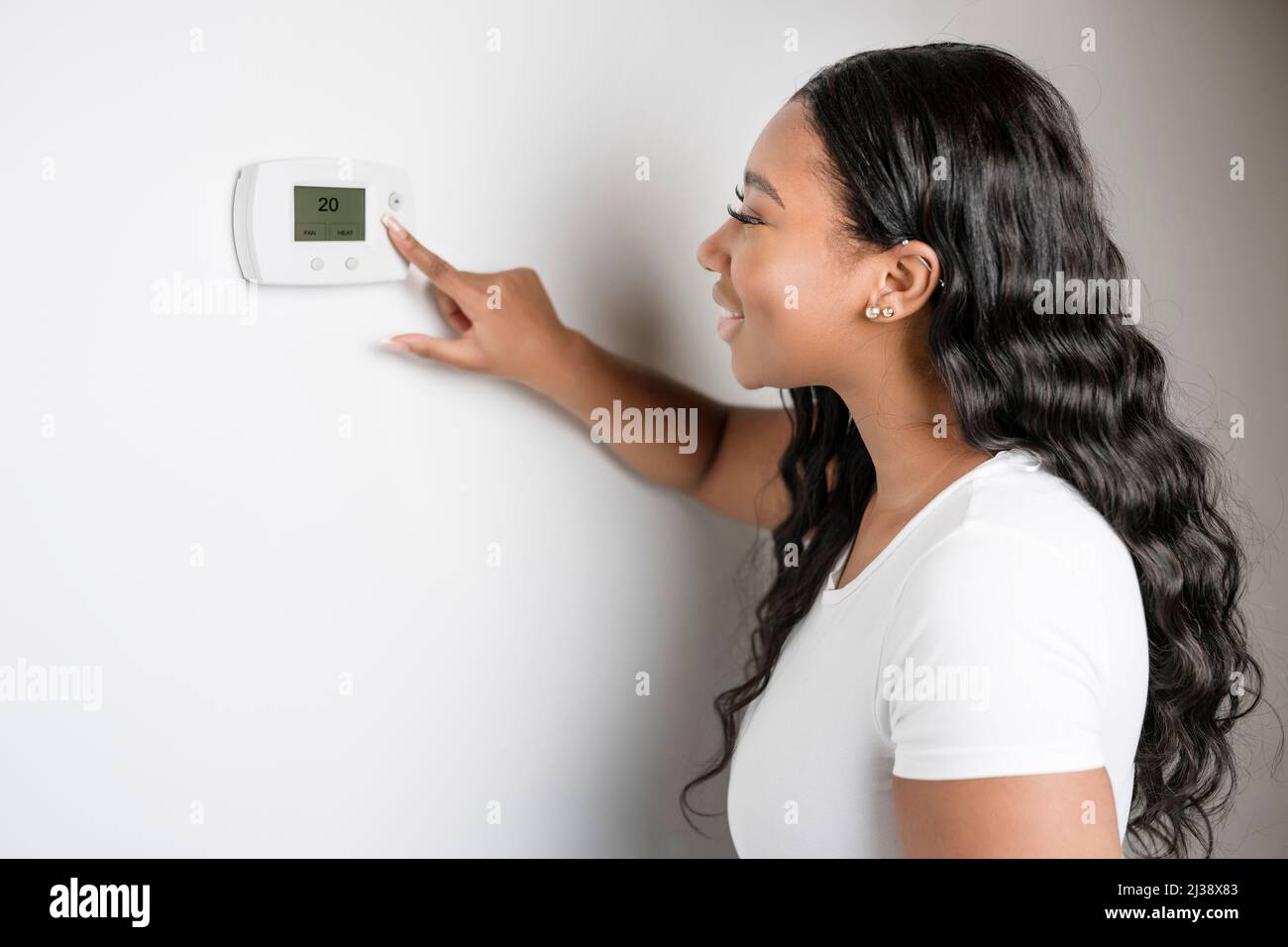 African woman lady adjusting the climate control panel on the wall wall ...