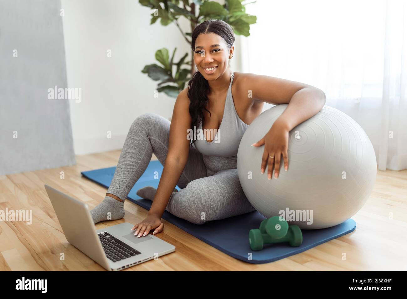 African american woman working out in home livingroom gym with laptop ...