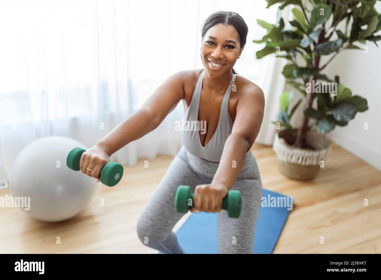 African american woman working out in home livingroom gym lift dumbbell ...