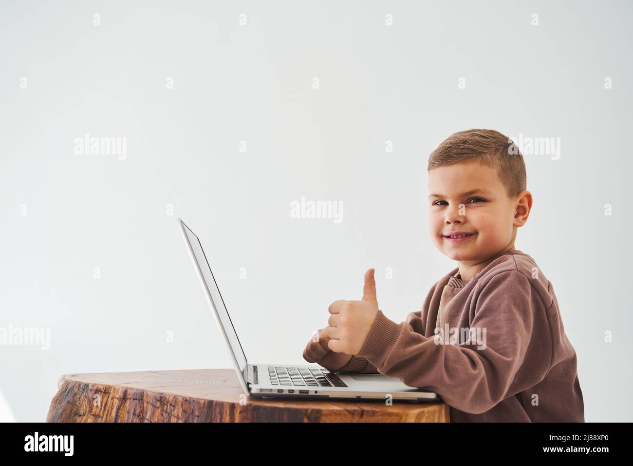 Child boy study online with laptop and shows thumbs up and smiles ...