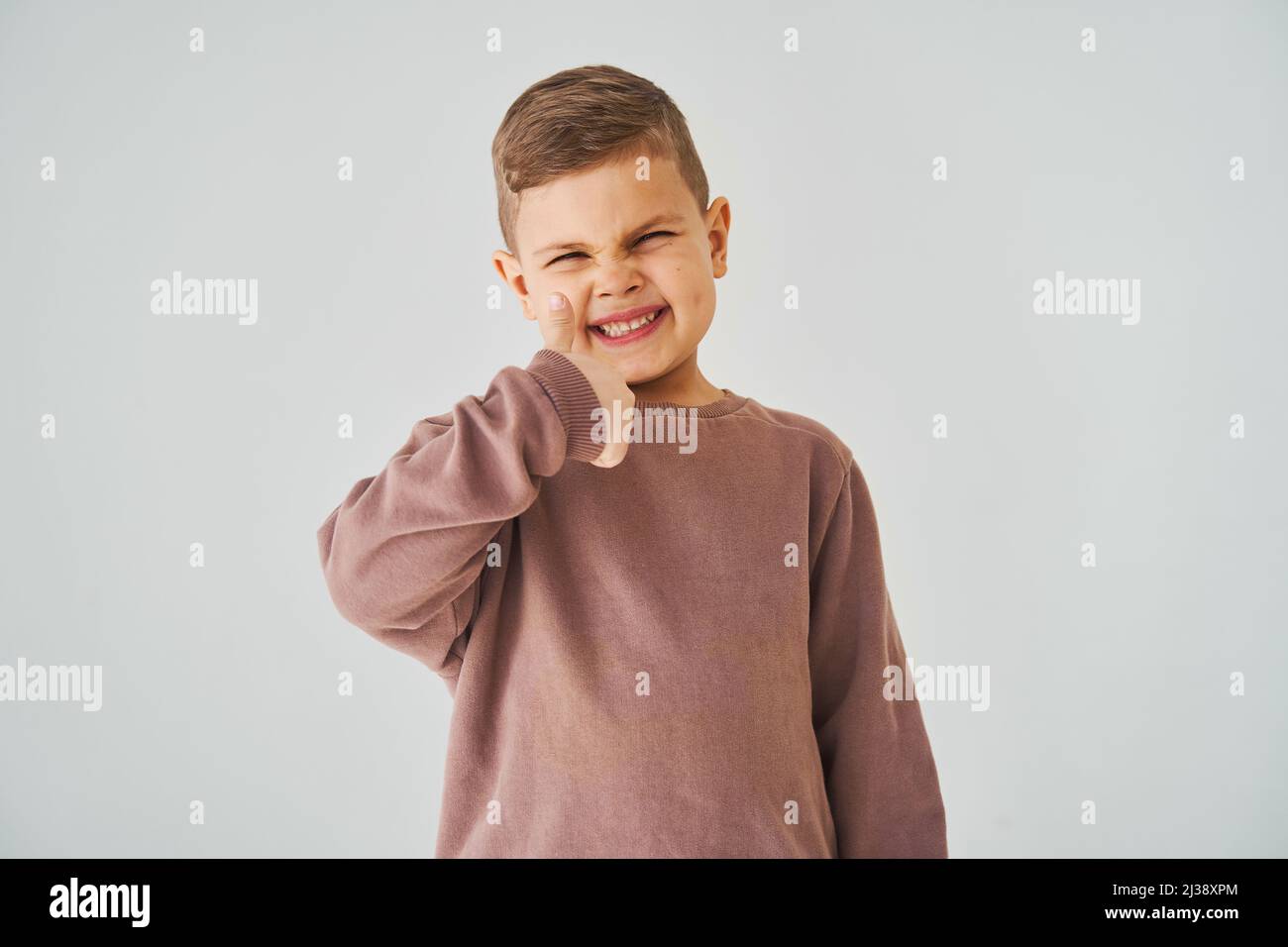 Happy child boy shows thumbs up and smiles on white background ...