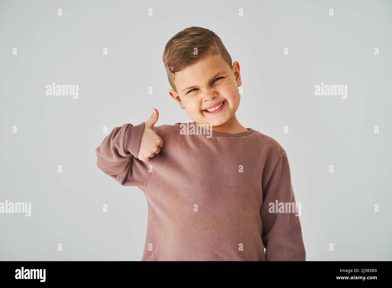 Happy child boy shows thumbs up and smiles on white background ...