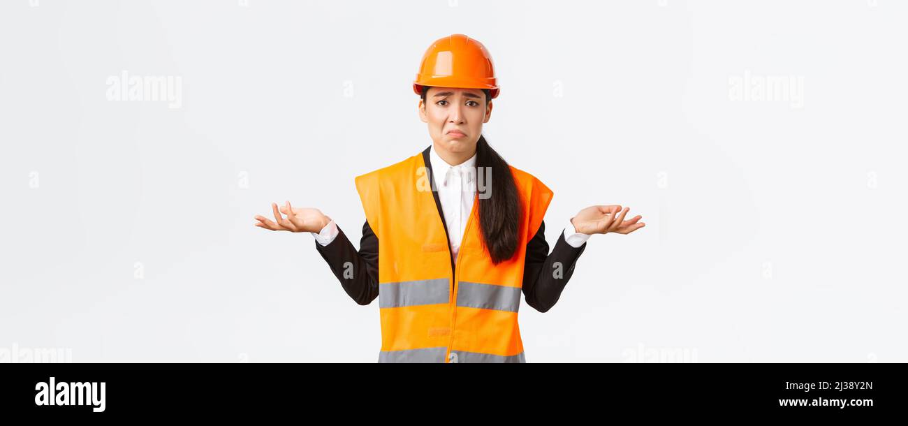 Upset and confused asian female engineer feeling complicated, raising ...
