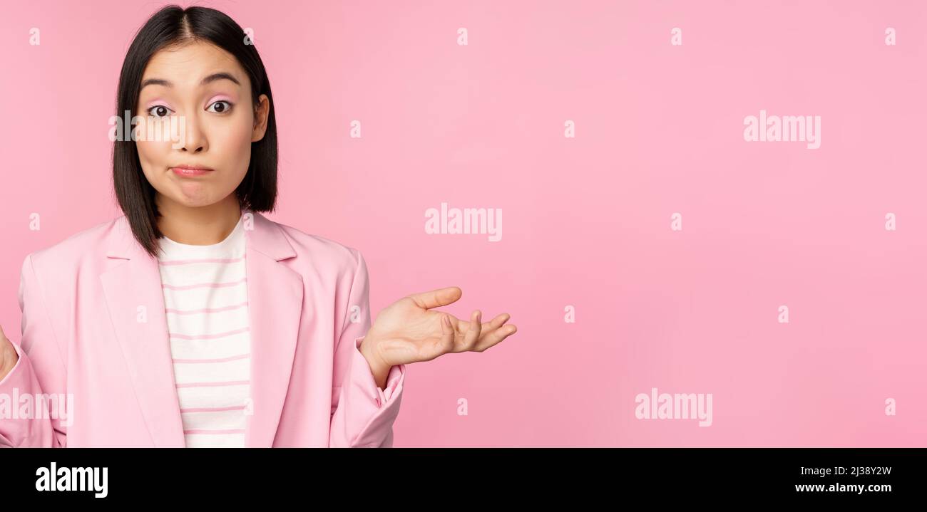 Portrait of confused asian businesswoman shrugging shoulders, looking ...