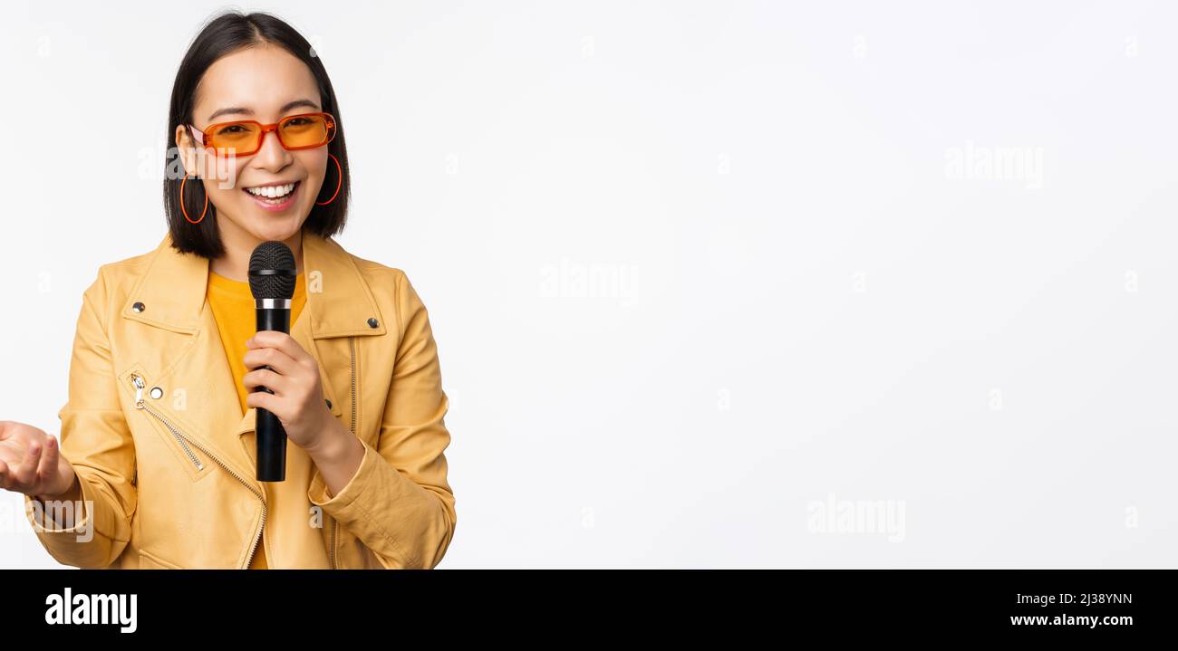 Portrait of beautiful asian woman in sunglasses, stylish girl singing ...